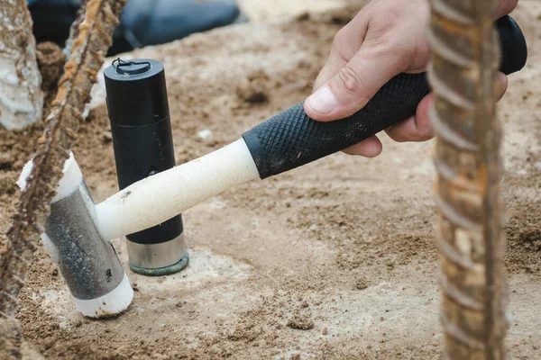 Seismic test on concrete pile. Engineer using the PIT Hand-Held Hammer ...
