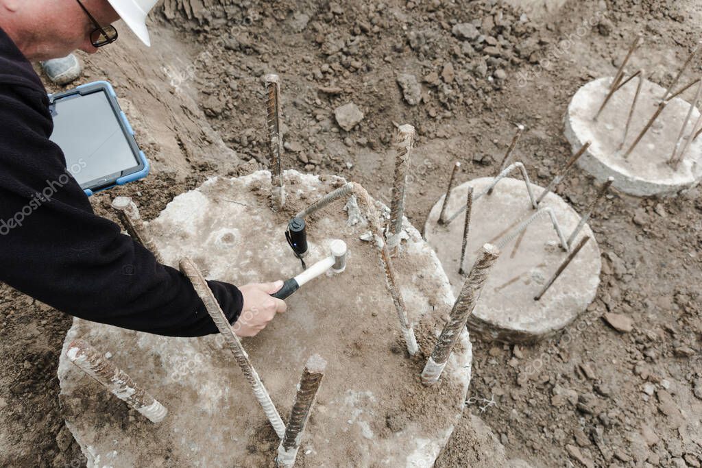 Seismic test on concrete pile. Engineer using the PIT Hand-Held Hammer ...