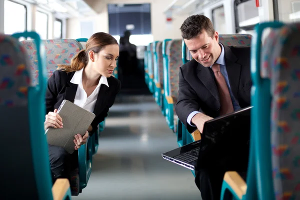 Businessman showing his college something on his computer. On the train ...