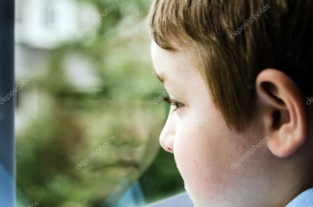 Sad child looking out window on gloomy day — Stock Photo © RobHainer ...