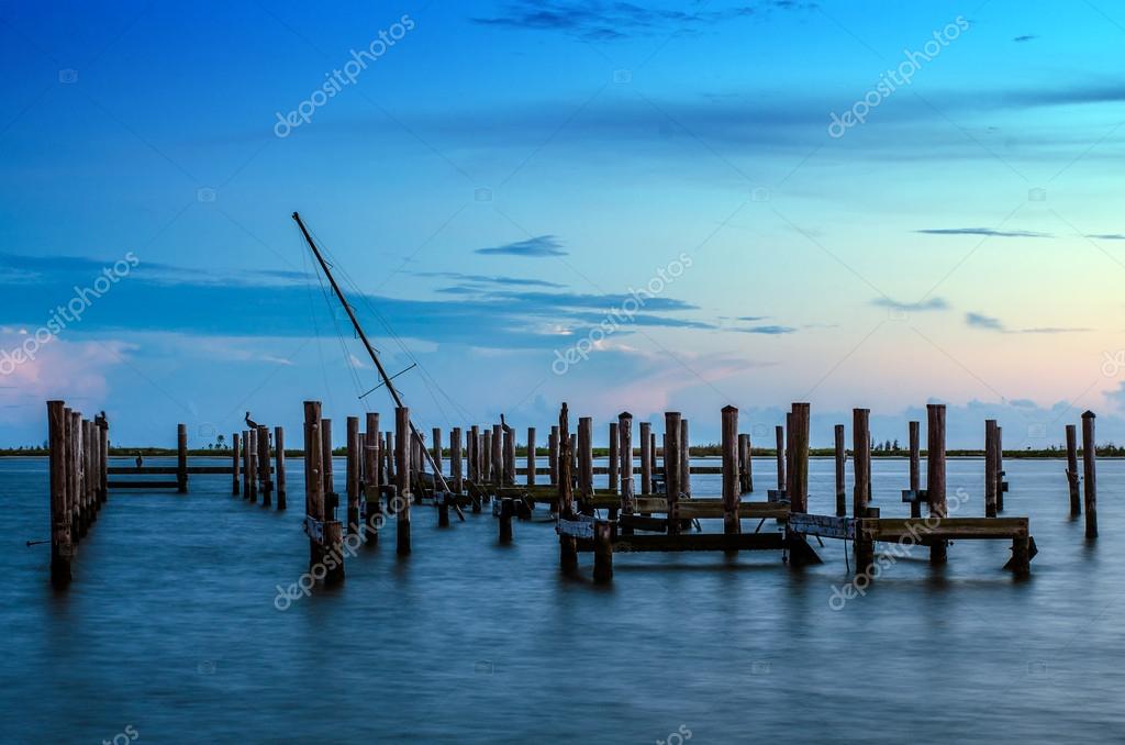 Broken pier and mast of broken ship in water after sunset in Biloxi ...
