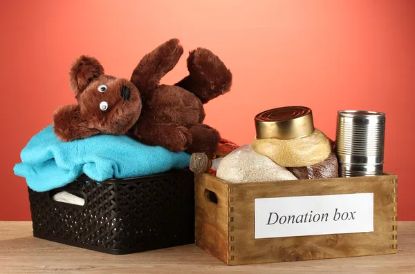 Donation boxes with clothing and food on red background close-up Stock ...
