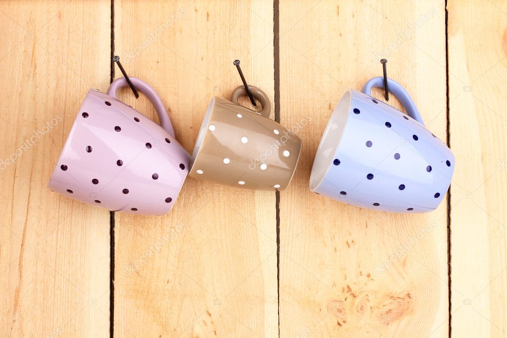 Nice cups hanging on nails on wooden background Stock Photo by ...