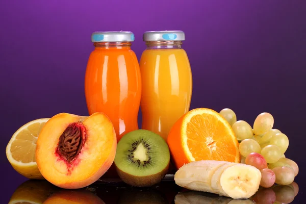 Delicious multifruit juice in a bottle and fruit next to it on yellow ...