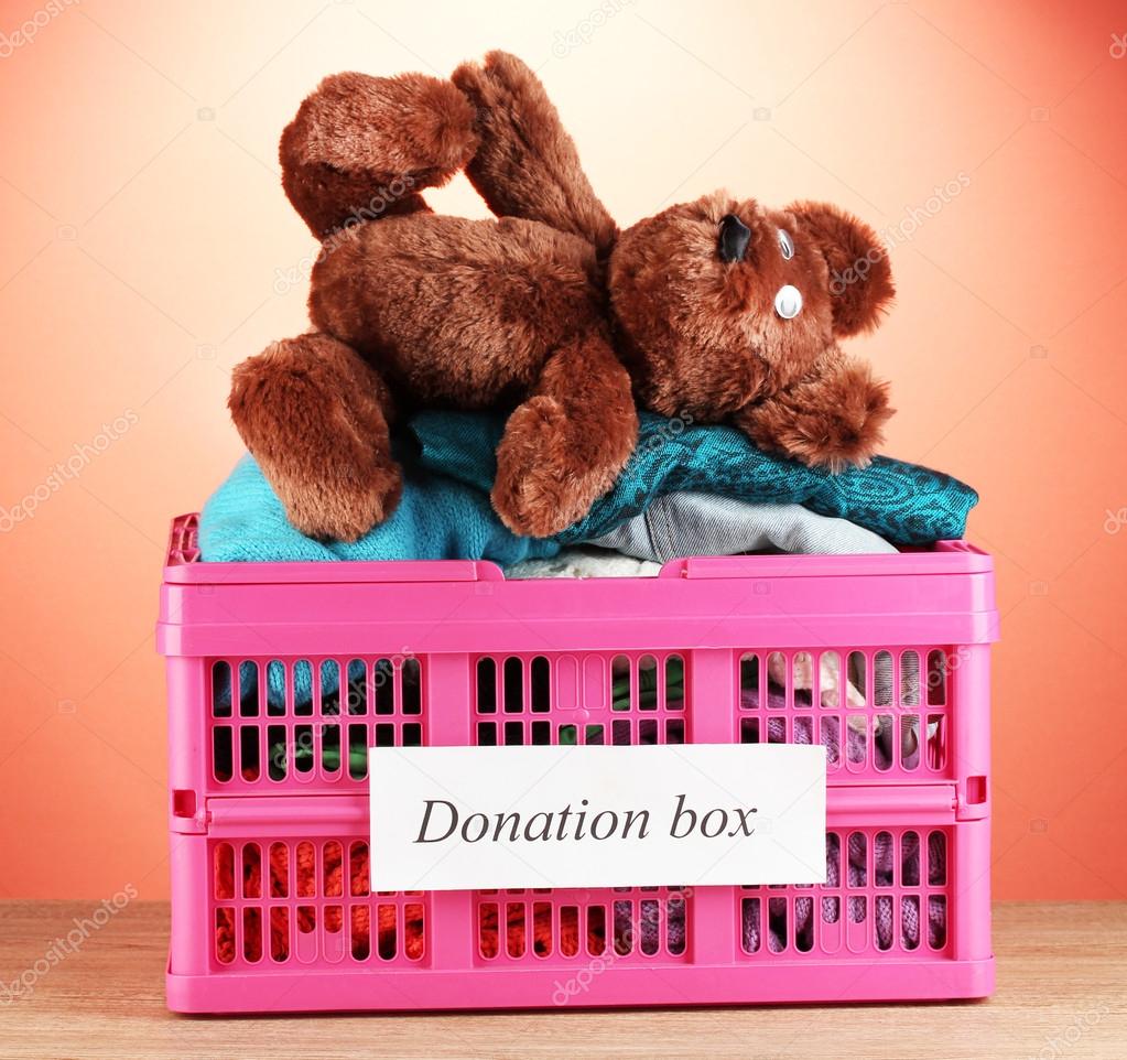 Donation box with clothing on red background close-up Stock Photo by ...
