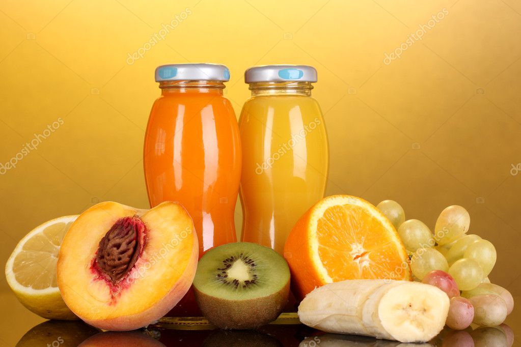 Delicious multifruit juice in a bottle and fruit next to it on yellow ...