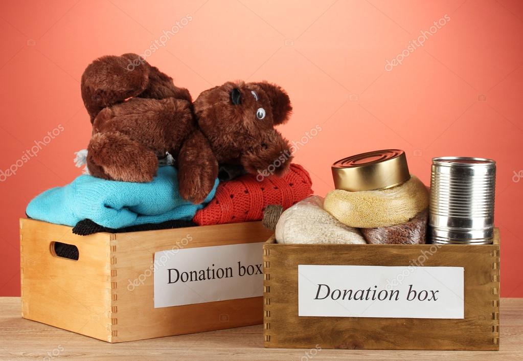 Donation boxes with clothing and food on red background close-up Stock ...