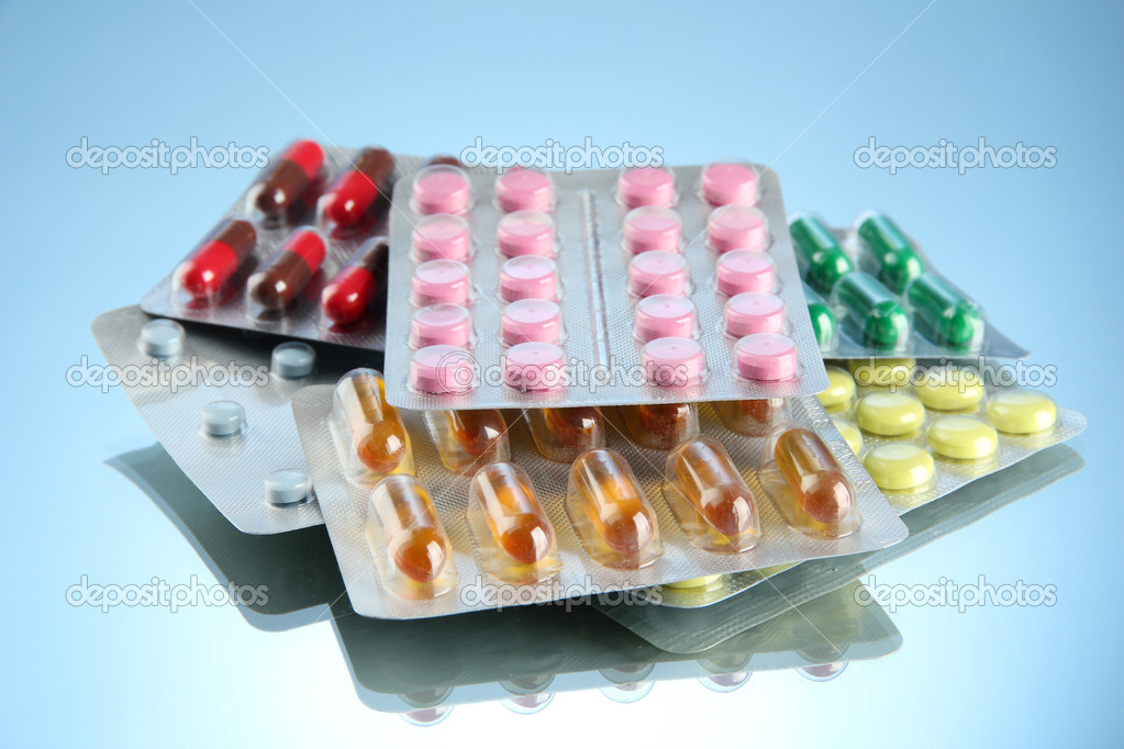 Capsules and pills packed in blisters, on blue background — Stock Photo ...