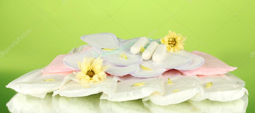 Various types of sanitary pads and tampons on green background close-up ...