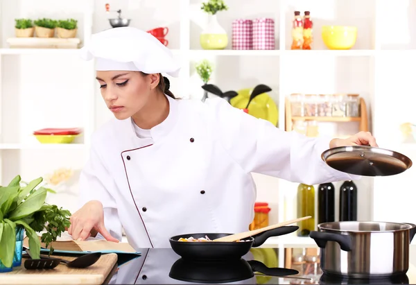 Young woman chef cooking in kitchen Stock Photo by ©belchonock 19159821