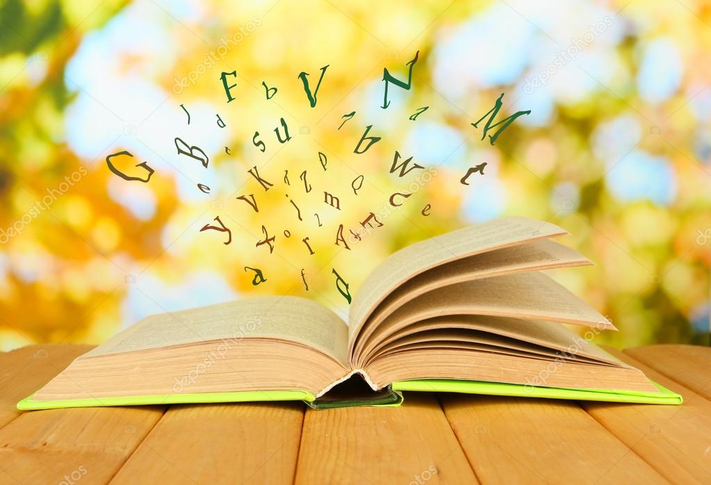 Opened book with letters flying out of it on bright background — Stock ...