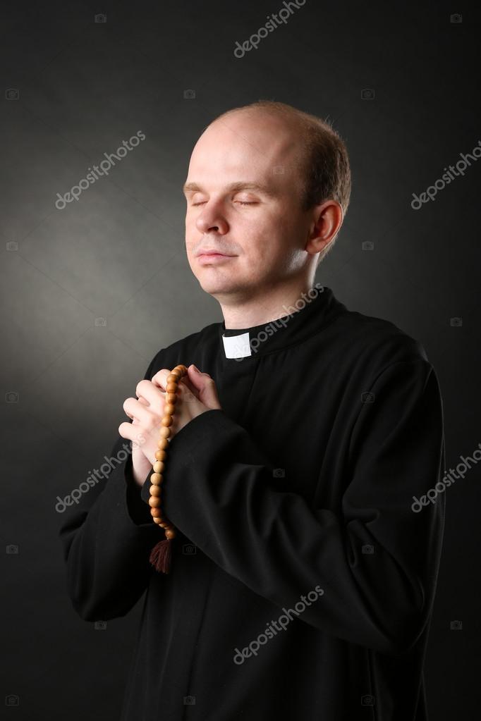 Priest with rosary on black background Stock Photo by ©belchonock 21771993