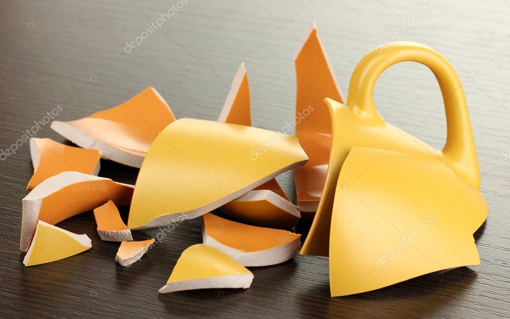 Copa rota amarilla sobre fondo de madera 2024