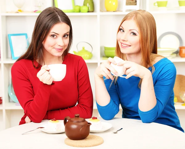 Two girl friends talk and drink tea in kitchen Stock Photo by ...