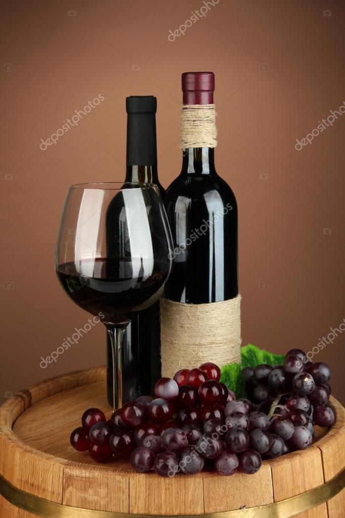 Composition of wine bottles, glass of red wine, grape on wooden barrel ...