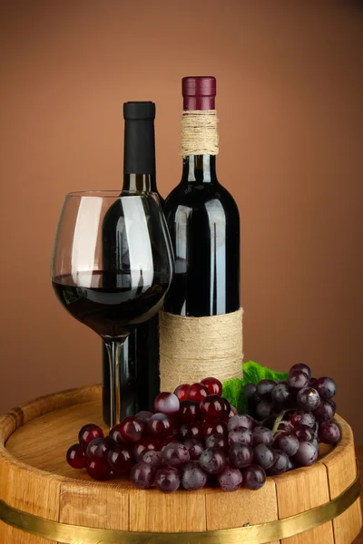 Composition of wine bottles, glass of red wine, grape on wooden barrel ...