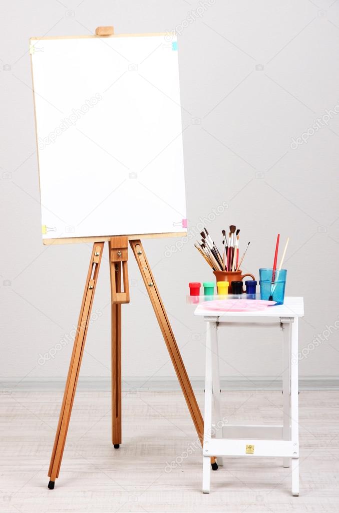 caballete de madera con papel limpio y artículos de arte en la ...