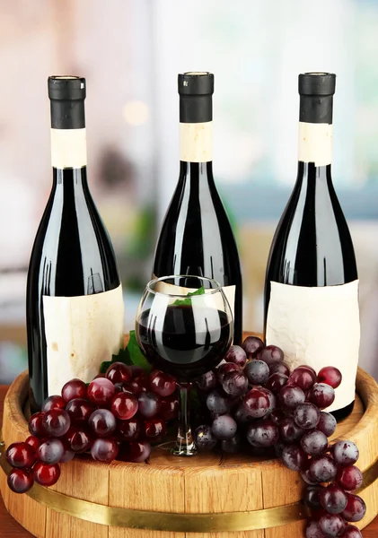Composition of wine bottles, glass of red wine, grape on wooden barrel ...