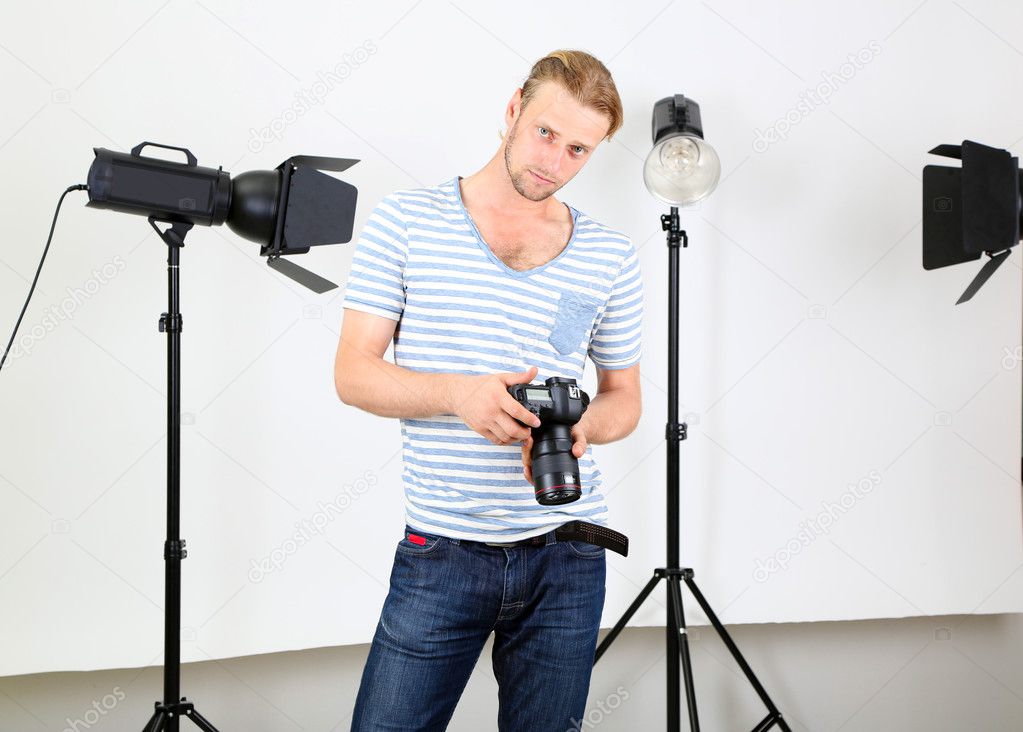 Handsome photographer with camera at working, on photo studio ...