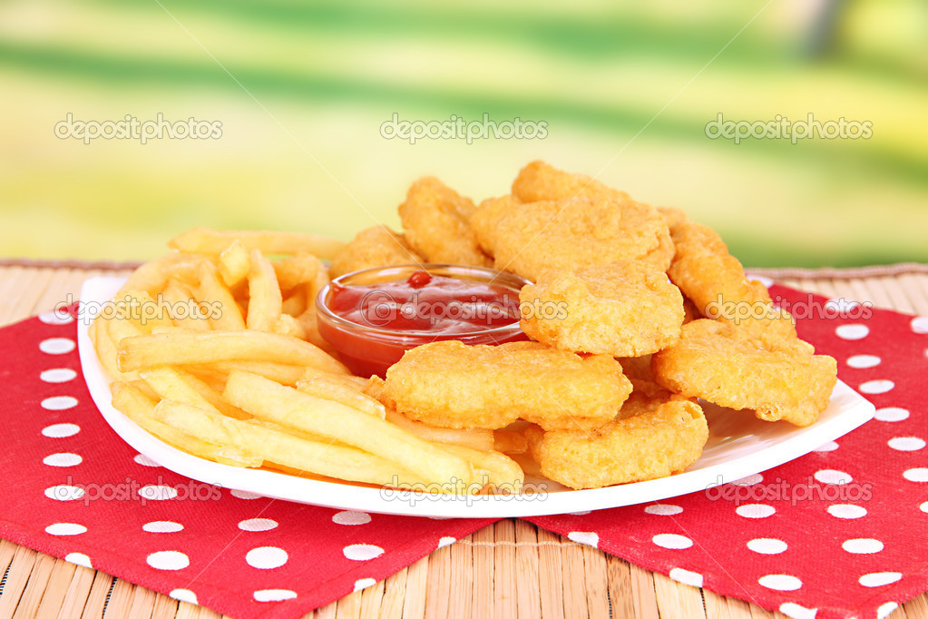 Fried chicken nuggets with french fries and sauce on table in park ...
