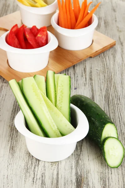 Bright fresh vegetables cut up slices in bowls on wooden table close-up ...
