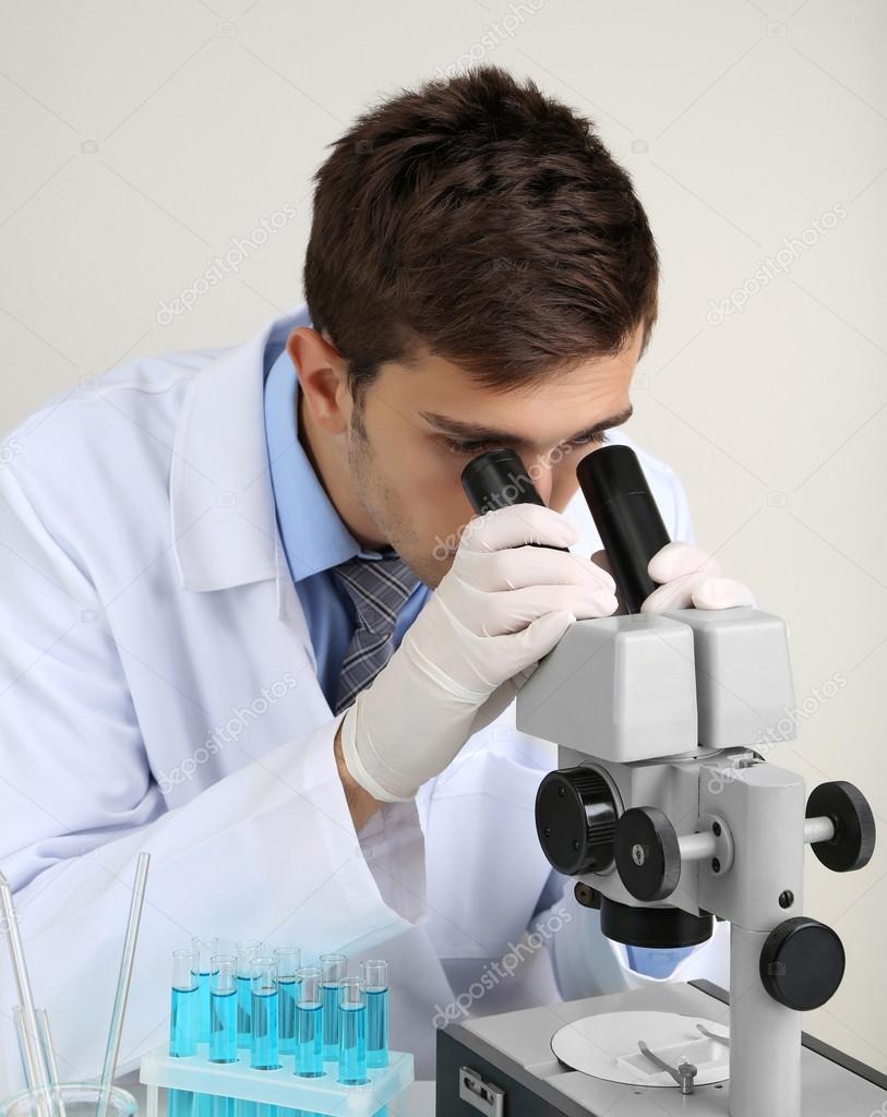 Científico de laboratorio joven mirando el microscopio en el ...