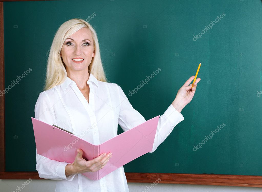 School teacher with folder near blackboard in classroom — Stock Photo ...