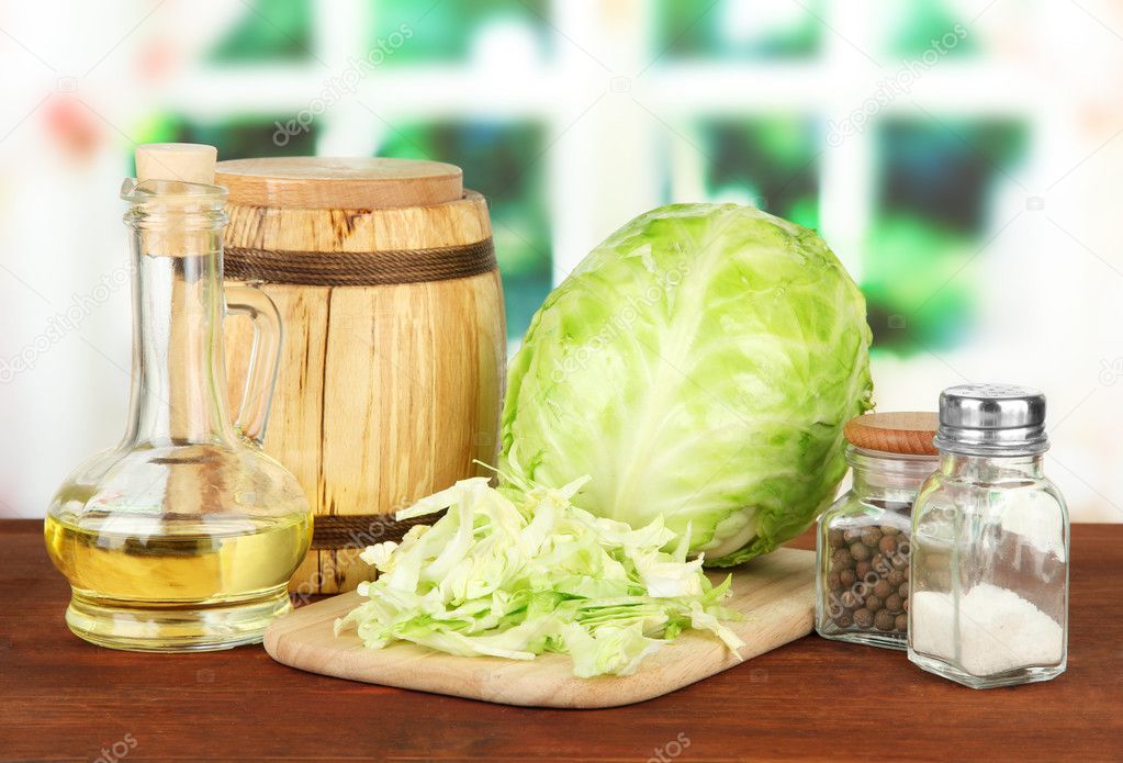 Green cabbage, oil, spices on cutting board, on bright background ...