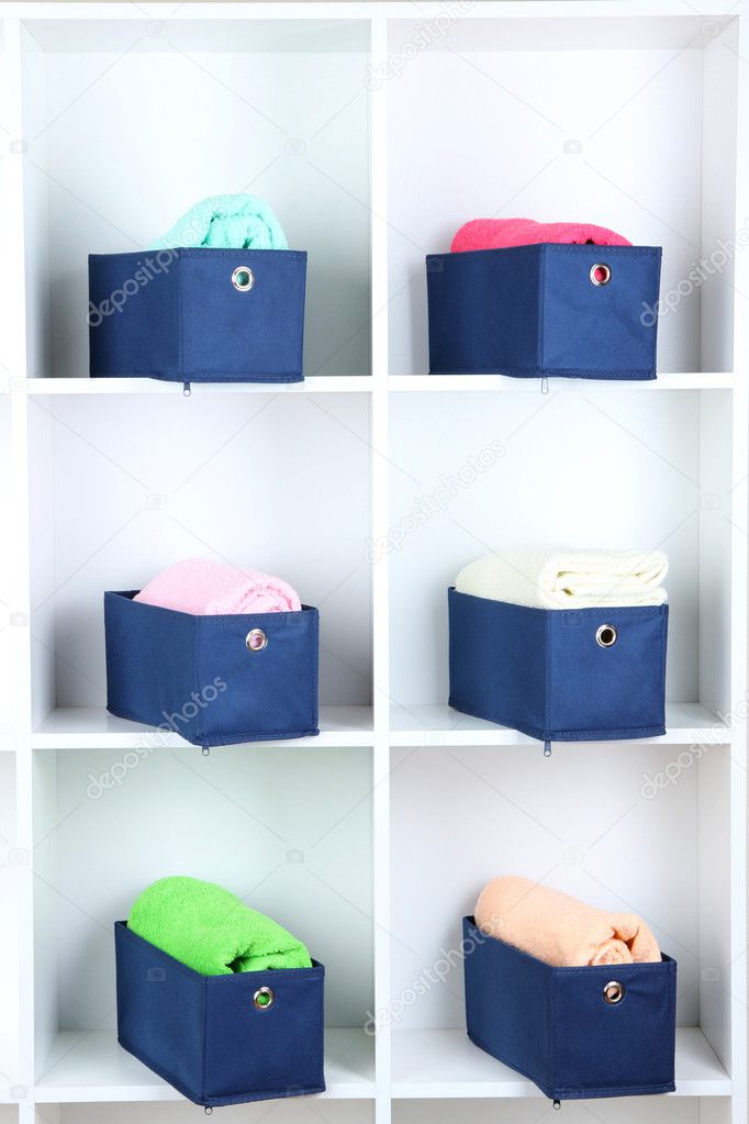 Blue textile boxes with towels in white shelves — Stock Photo ...