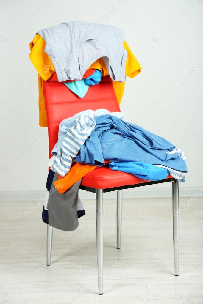 Heap of clothes on color chair, on gray background — Stock Photo ...