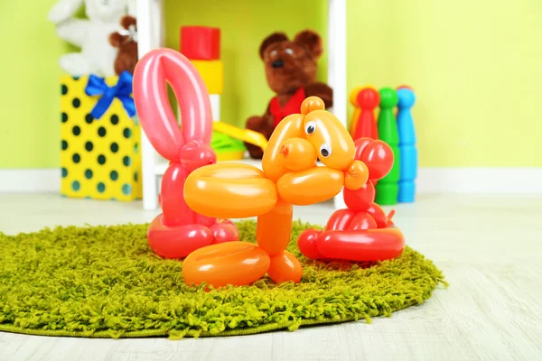 Simple balloon animals and other toys on shelves, on bright background ...