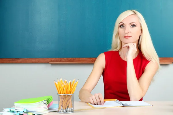 School teacher sitting at table on blackboard background Stock Photo by ...