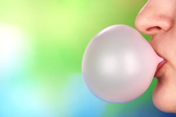 Person doing bubble with chewing gum on bright background - Stock Image ...