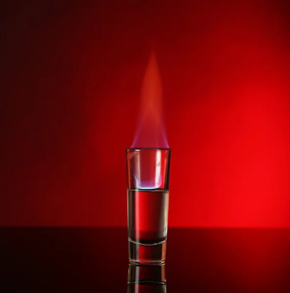 Glass with burning alcohol on red background - Stock Image - Everypixel