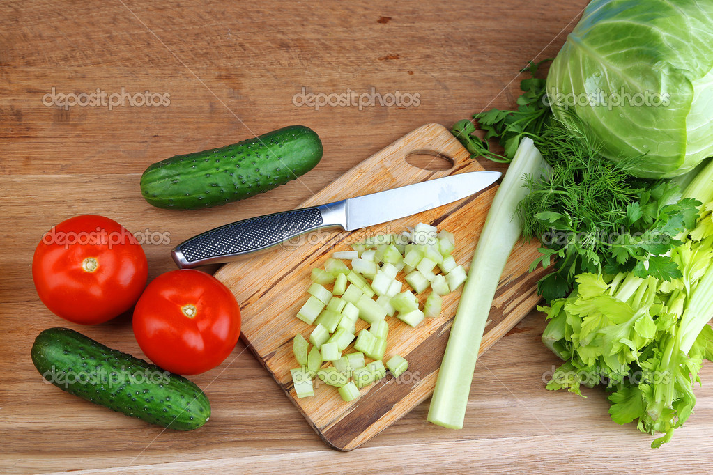 Composición con apio picado sobre tabla de madera y verduras frescas ...