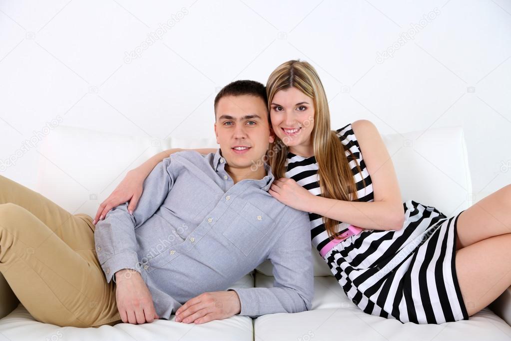 Loving couple sitting on sofa, on light background — Stock Photo ...