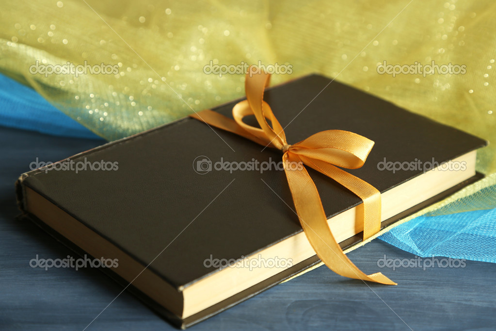 Book wrapped with color ribbon, on wooden background Stock Photo by ...
