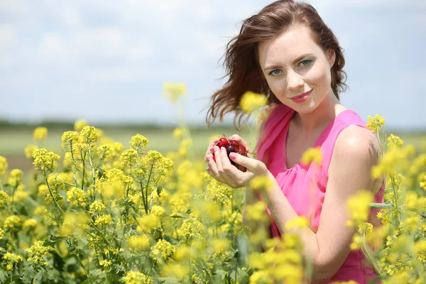 Beautiful young woman with cherries in field - Stock Image - Everypixel