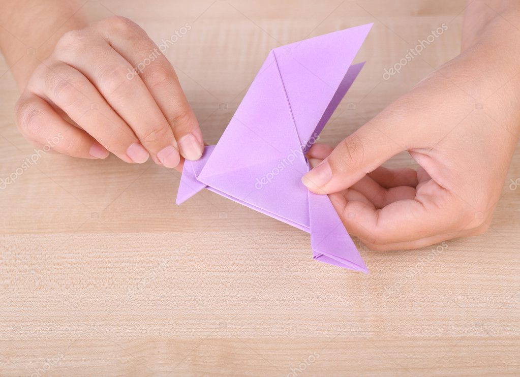 Female hands holding origami bird — Stock Photo © belchonock #50000653