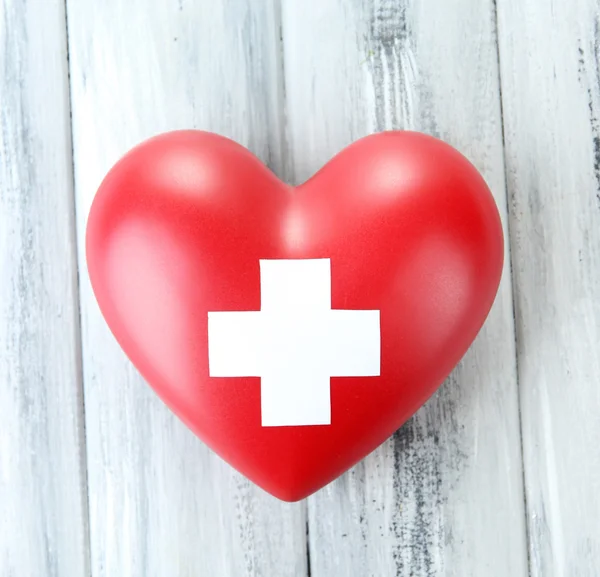 Red heart with cross sign in female hand, close-up, on light background ...