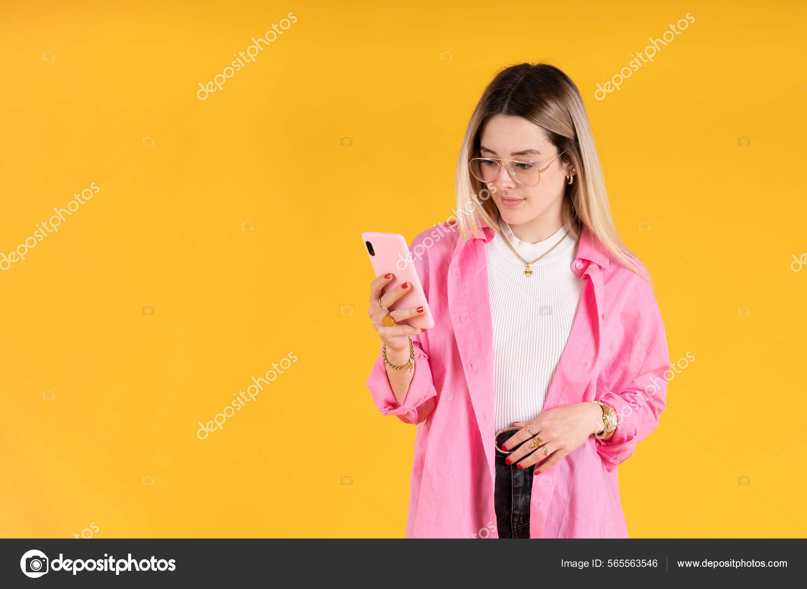 Young woman standing using her cell phone on yellow background Stock ...