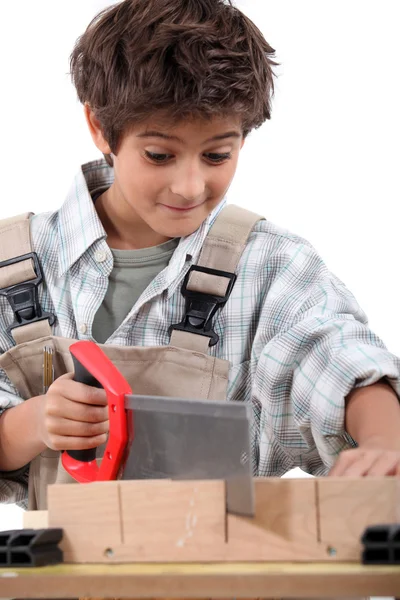 Young boy dressed as a carpenter sawing wood Stock Photo by ...