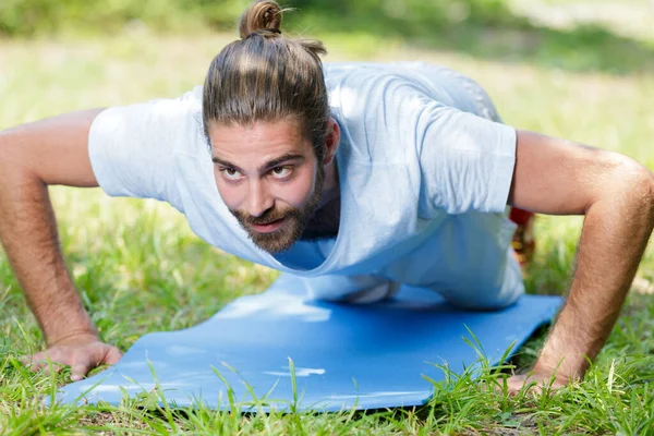 young man in plank position exercising outdoors - Stock Image - Everypixel