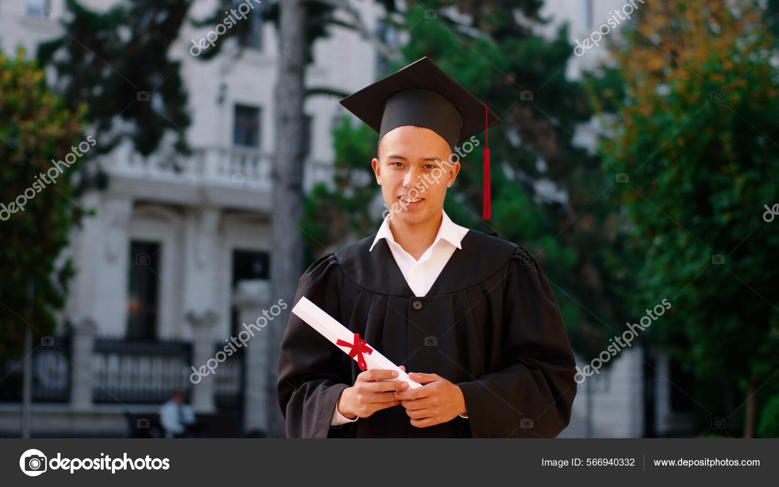 Happy charismatic graduate guy holding his diploma and posing in front ...