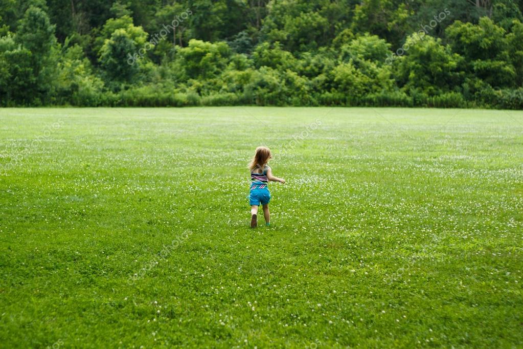 Small child running through field towards woods — Stock Photo ...