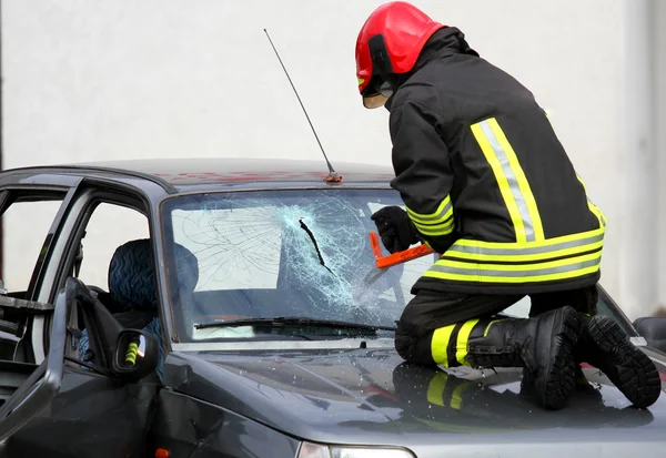 Fireman with work gloves while breaking a car windshield to rele ...