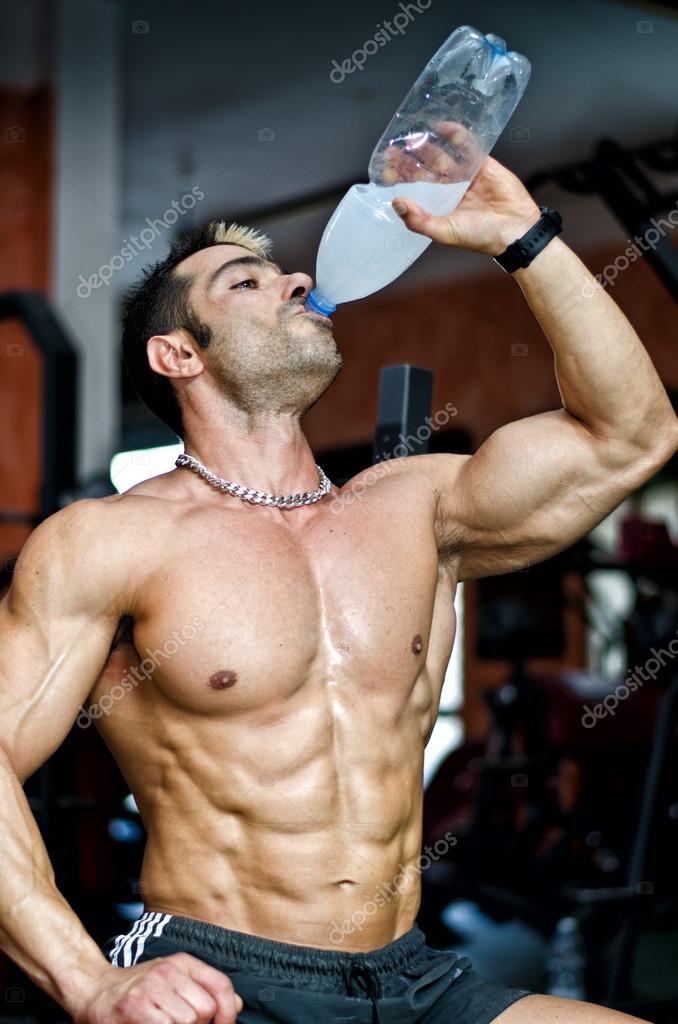 Muscular male bodybuilder drinking water or energy drink — Stock Photo ...