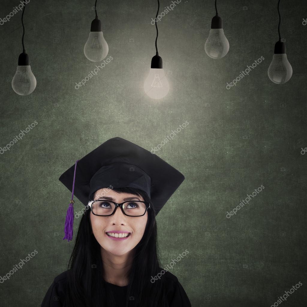 Smart graduate looking at lit bulb — Stock Photo © realinemedia #28831721
