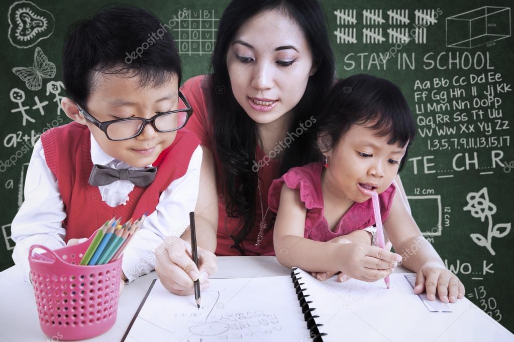 Beautiful teacher help children write letters in class — Stock Photo ...