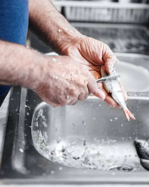 Man hands are cleaning fresh fish in kitchen sink with knife, cooking ...